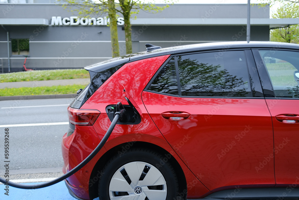 red Volkswagen car hybrid on street, charging with electricity through ...