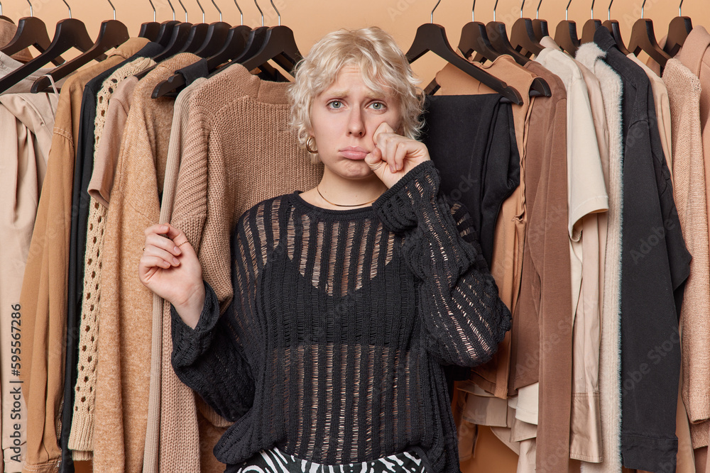 Stressed unhappy woman has nothing to wear cries and wipes tears wears ...