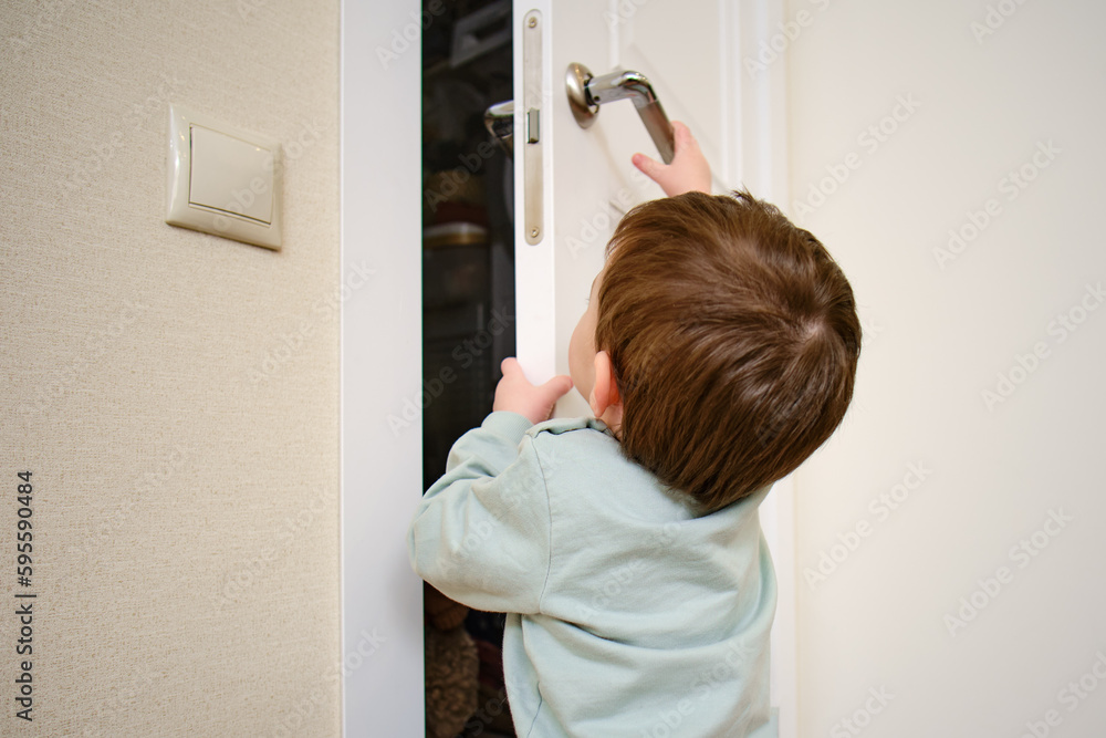 Little baby opens the door. Child pulls the door handle with the lock ... Little baby opens the door. Child pulls the door handle with the lock ...