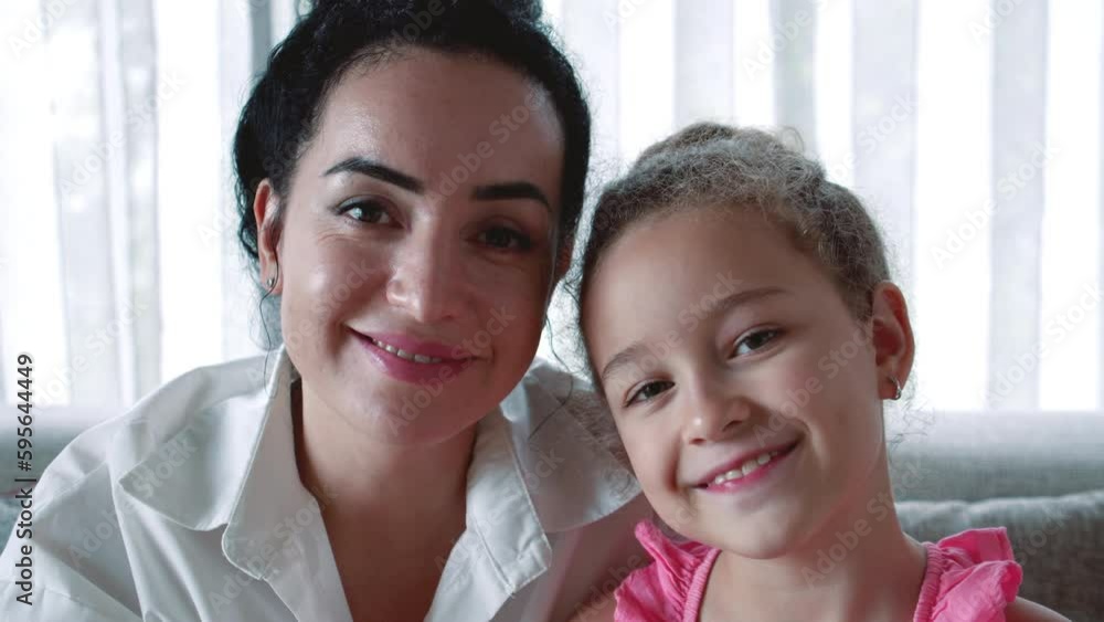 Pretty smiling child daughter embrace mom look at camera. Happy ...