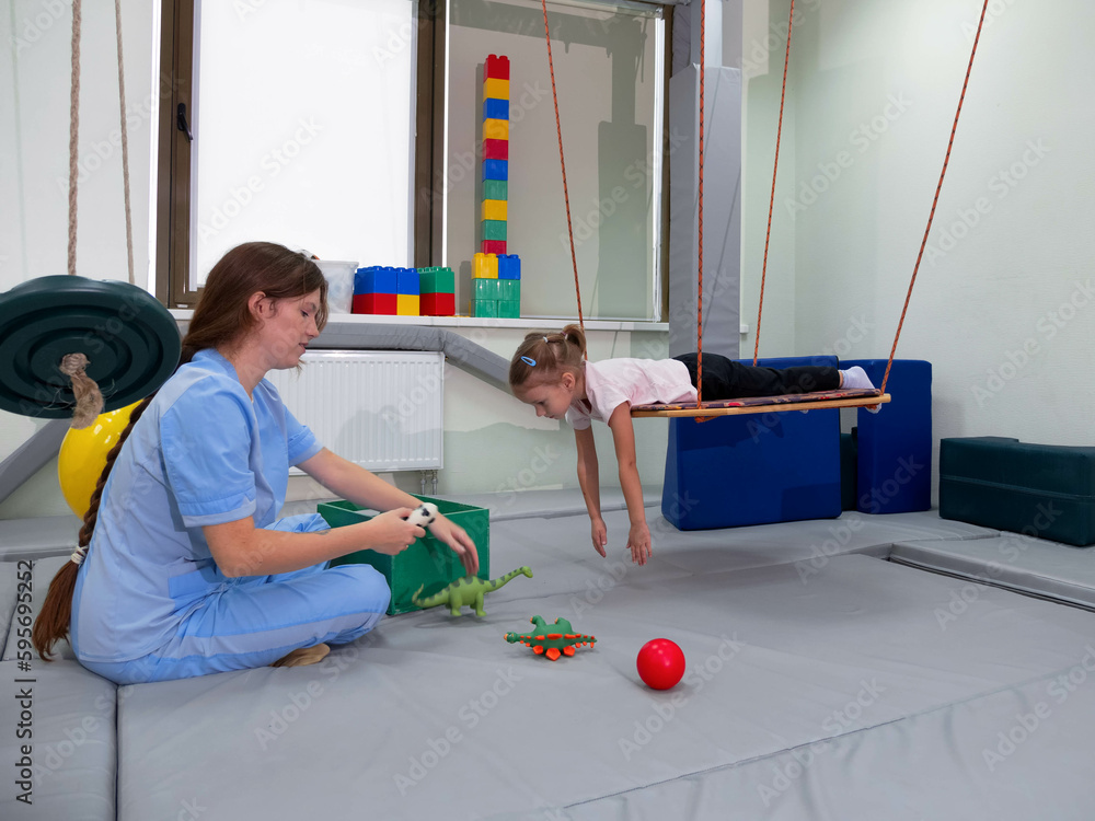 Child with physiotherapist on swing during sensory integration session ...