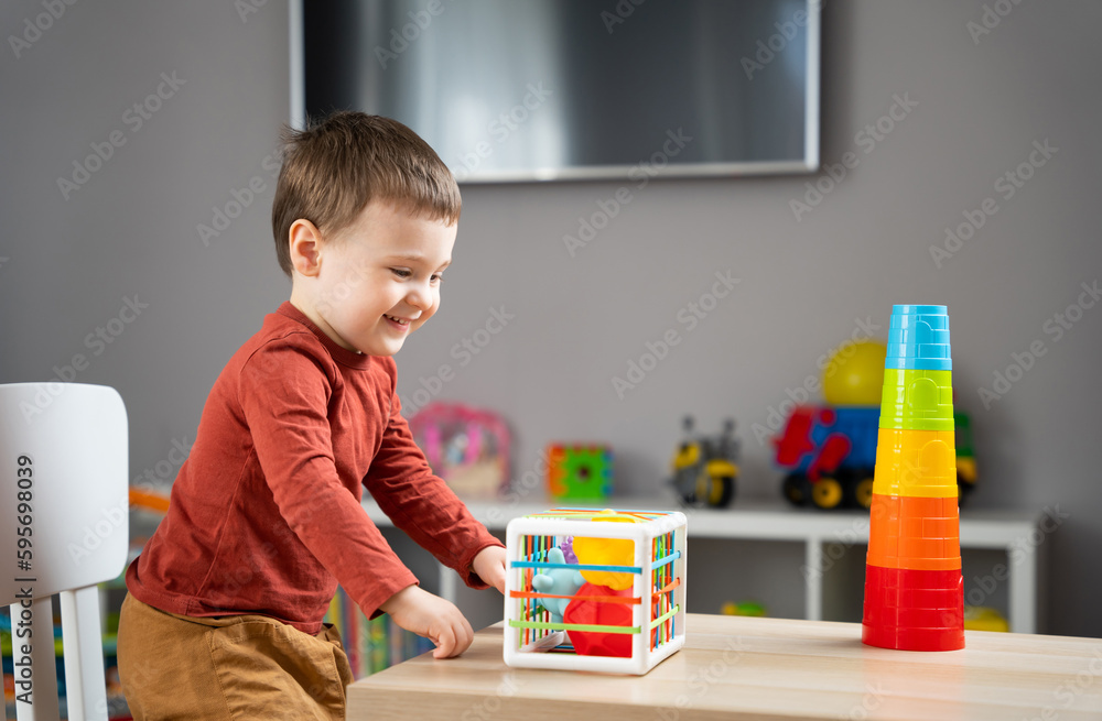 A cute little toddler boy of two years old plays with multi-colored ...