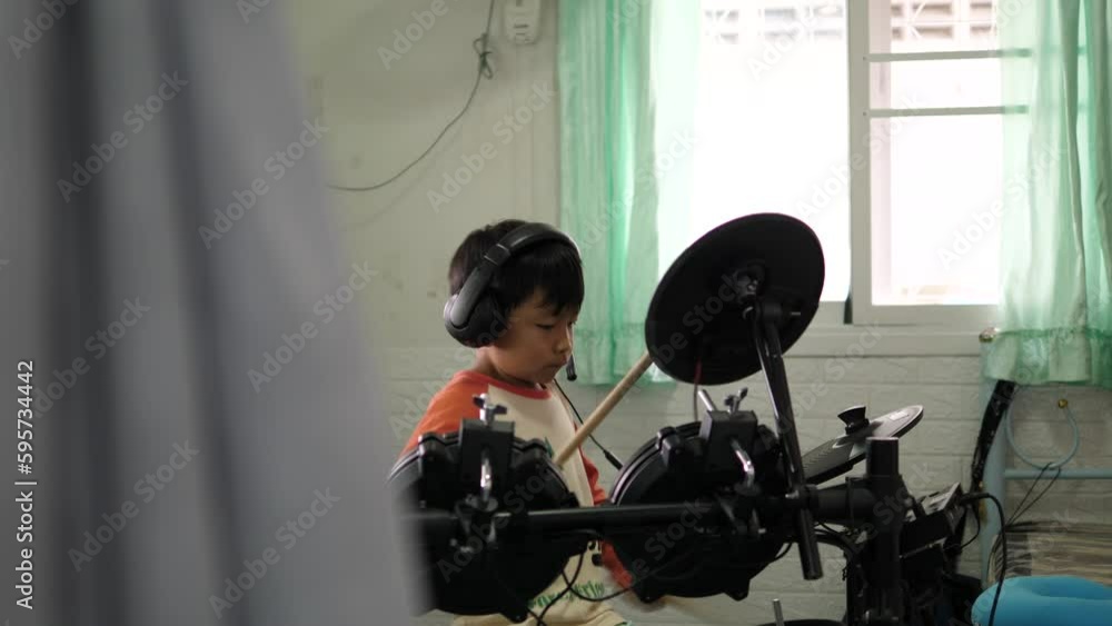 Asian child boy play electronic drum with headphone. Kid beat drumstick ... Asian child boy play electronic drum with headphone. Kid beat drumstick ...