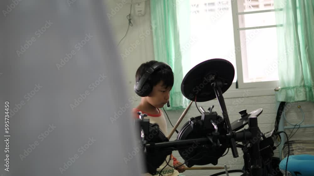 Asian child boy play electronic drum with headphone. Kid beat drumstick ... Asian child boy play electronic drum with headphone. Kid beat drumstick ...