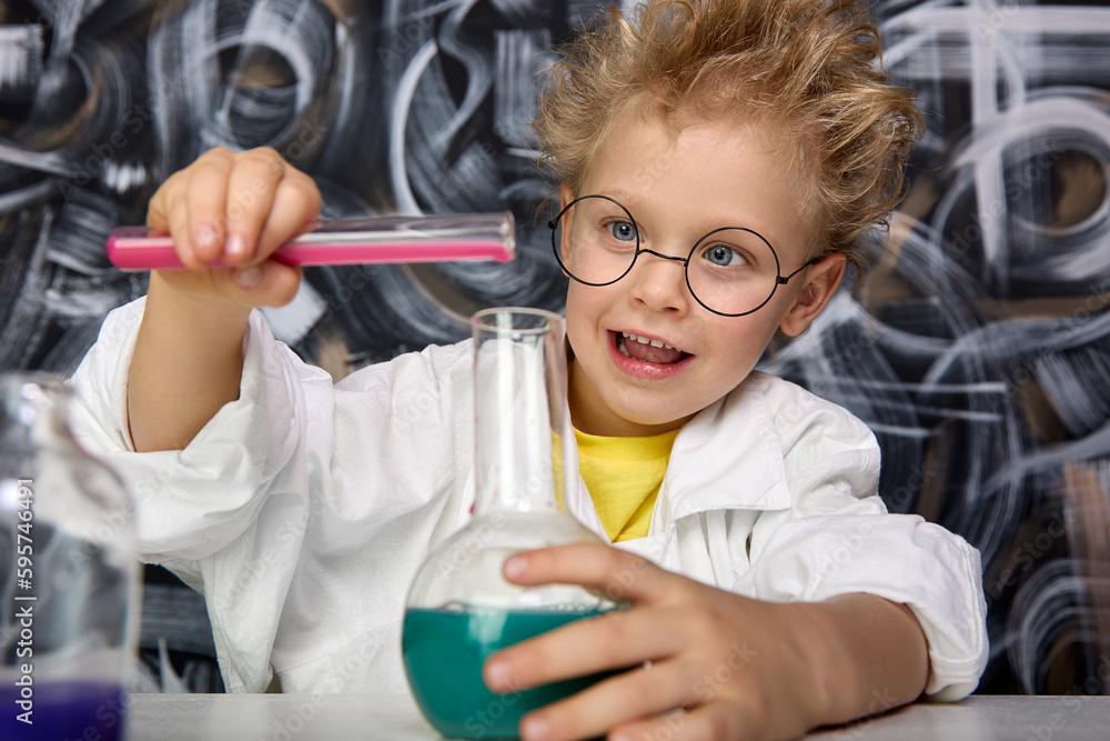 Happy child plays with chemical experiments, mixes colors in a test ...