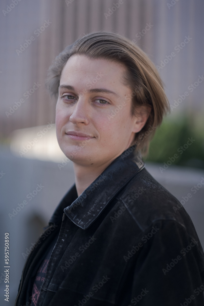 A gender fluid model in a black denim jacket and combed-back hair ...