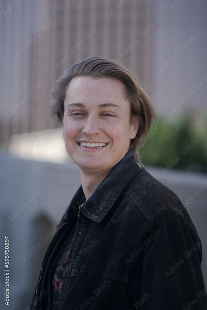 A gender fluid model in a black denim jacket and combed-back hair ...