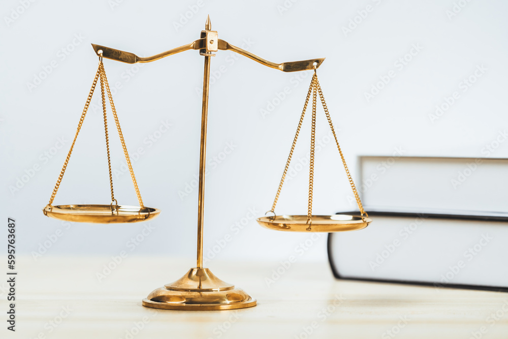 Shiny golden balanced scale and law book on desk in law school as ...