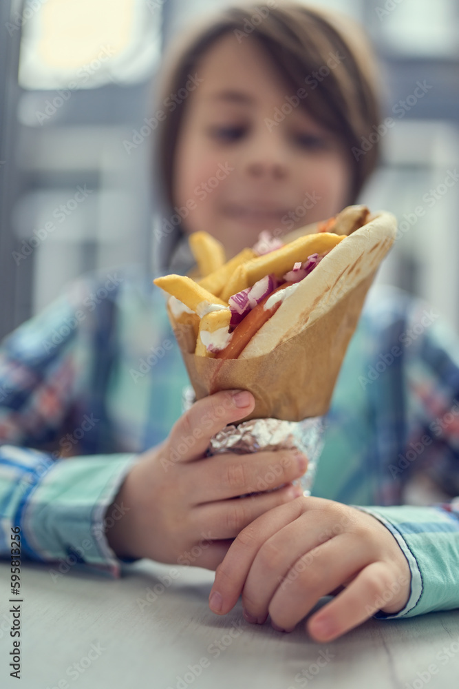 Cute little boy eating Greek gyros sandwich in a fast food restaurant ...