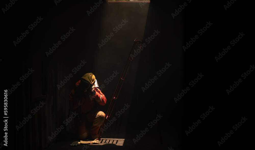 Firefighter is sitting next to a red ladder in a dark room a soft light ...