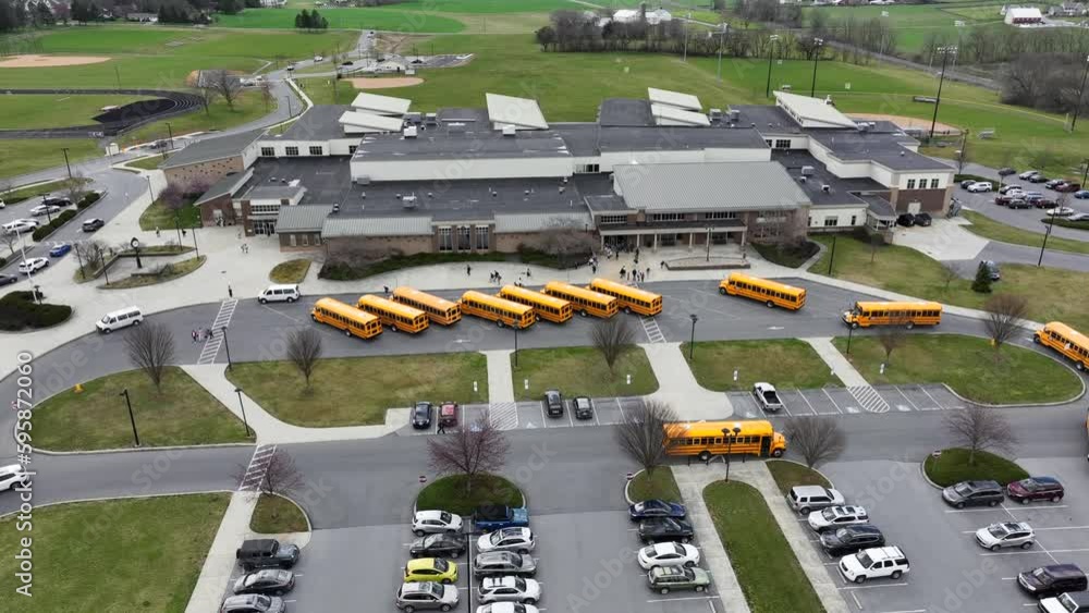 Aerial of public school campus in USA with yellow school bus vehicle to ...