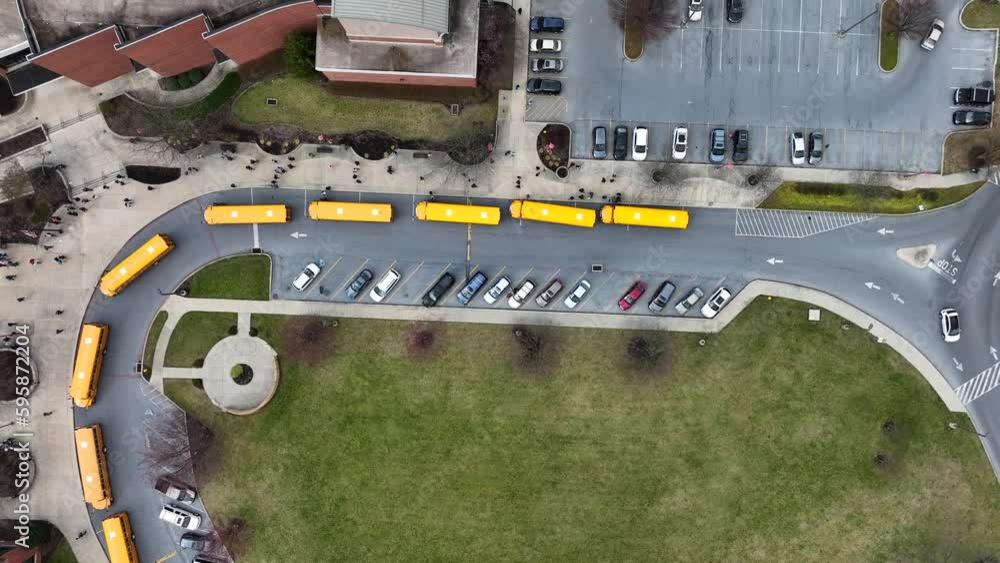 School bus line at school with students leaving building. Top down ...