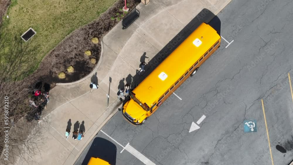 Students enter school bus at American school campus. Top down aerial ...