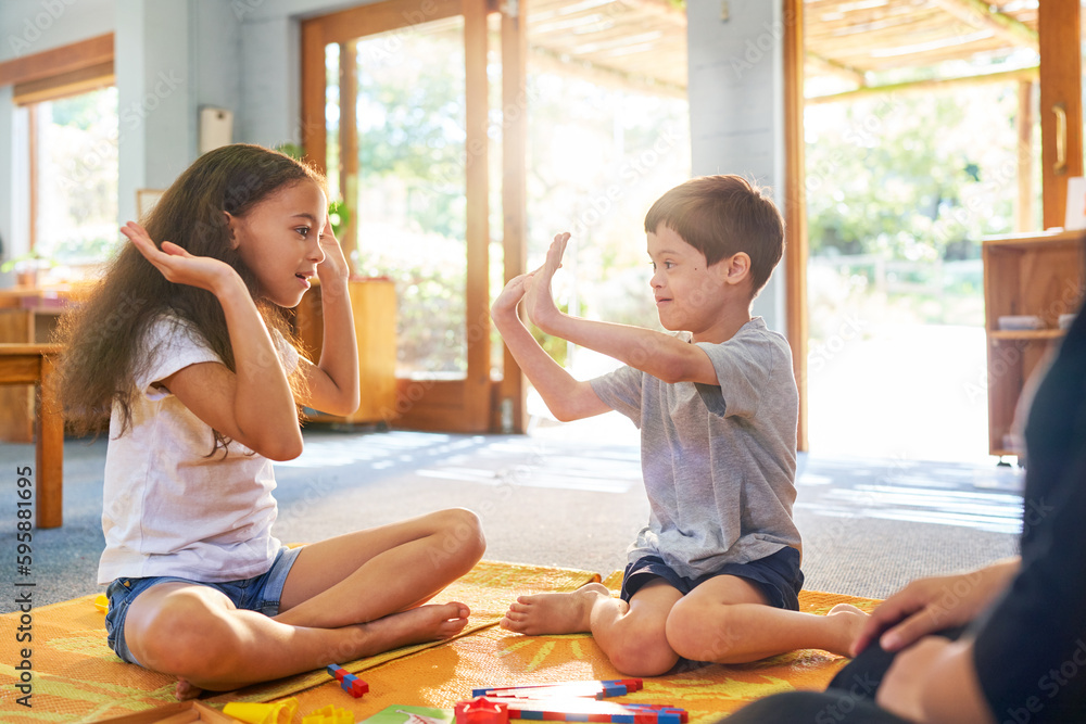 Sister playing clapping game with brother with Down Syndrome at home ...
