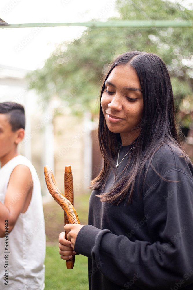 Aboriginal teenage girl with musical sticks in her backyard with her ...