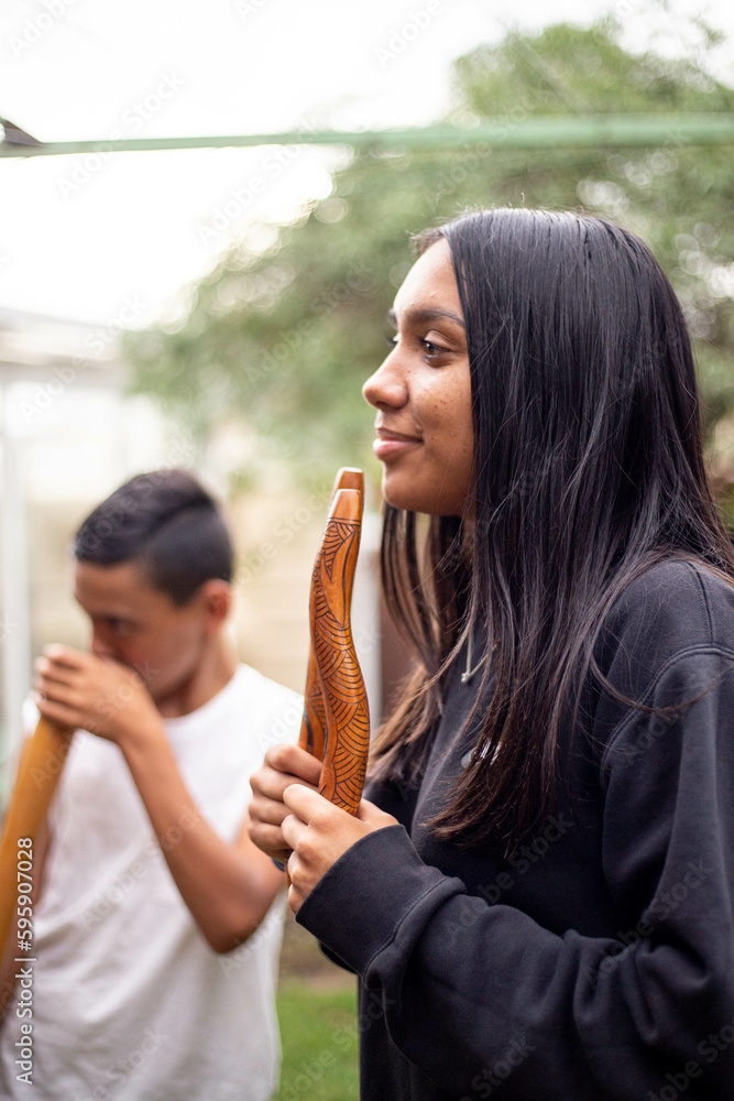 Aboriginal teenage girl with musical sticks in her backyard with her ...