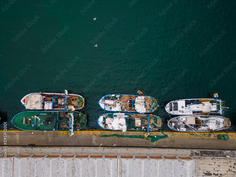 An aerial view of fishing boats in the port reveals the vibrant colors ...