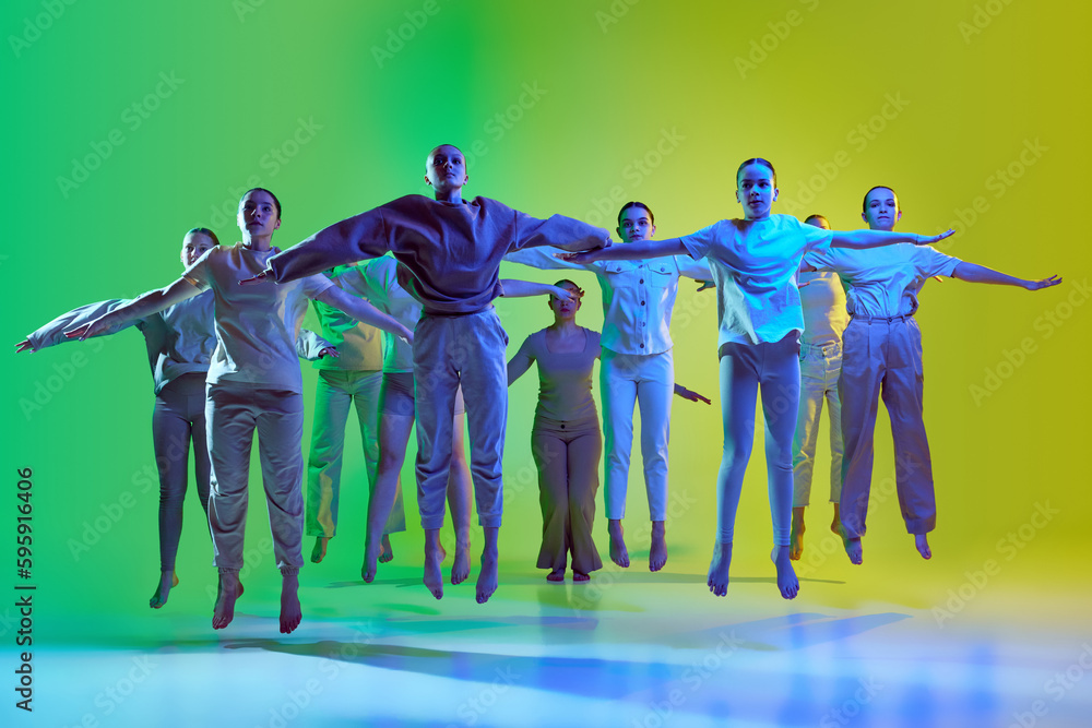 Group of teenagers, young dancers jumping together over green and ...