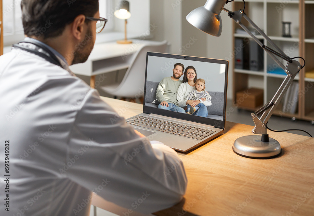 Doctor sitting at his table with his modern laptop computer, using a ...