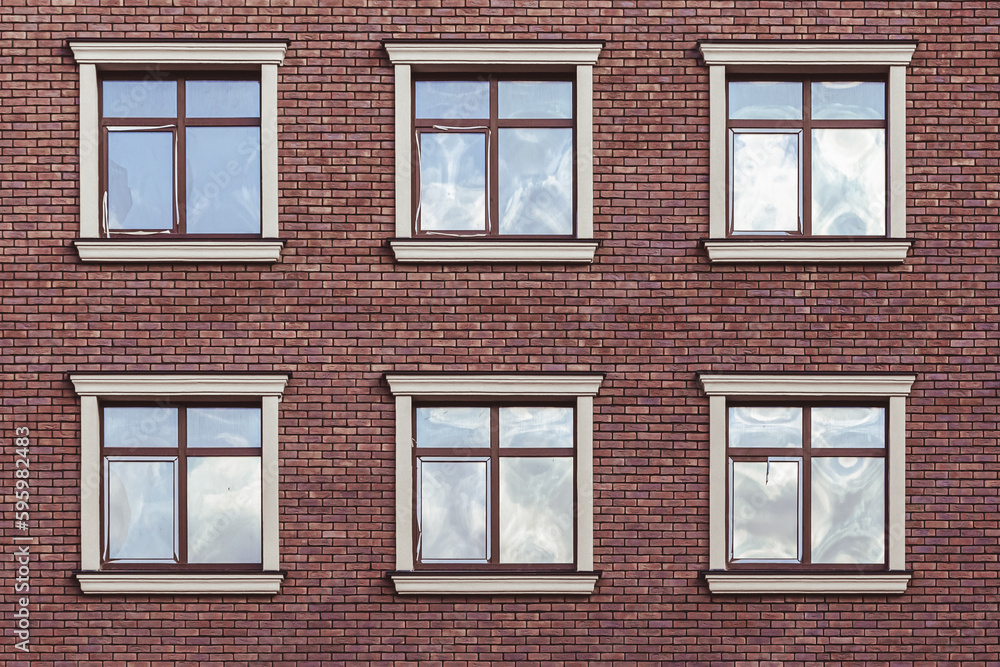 The facade of a brick house with identical square windows. Facade of ...