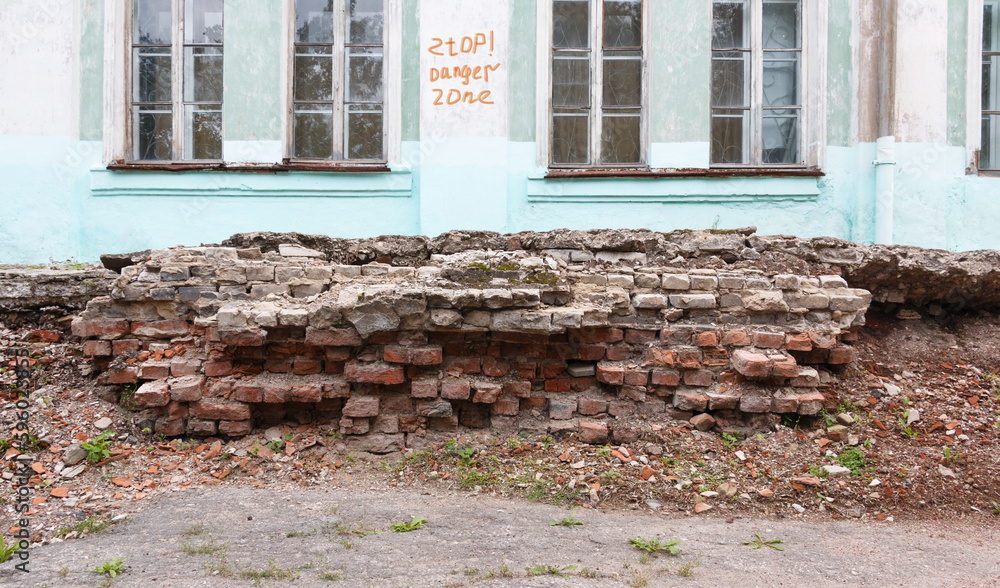 the crumbling foundation of the building. An old brick wall with ruined ...