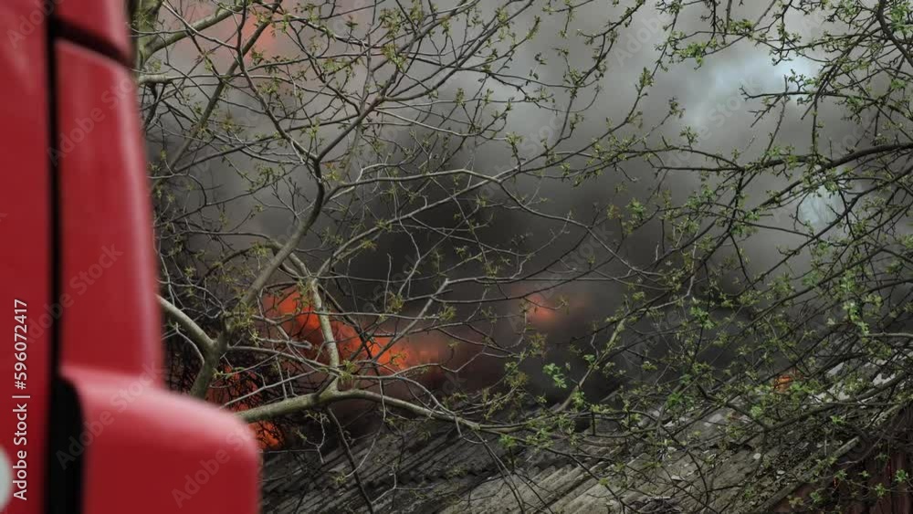 Close-up of the burning roof of a village house. Fire truck on the ...