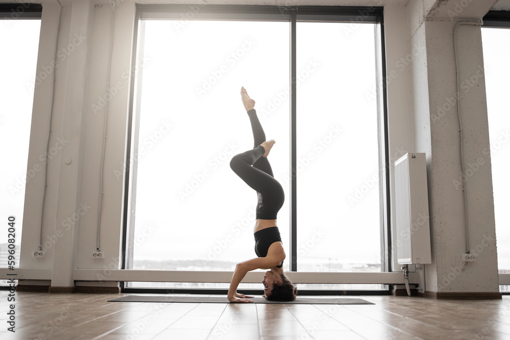 Professional female yoga trainer standing on her forearm with legs ...