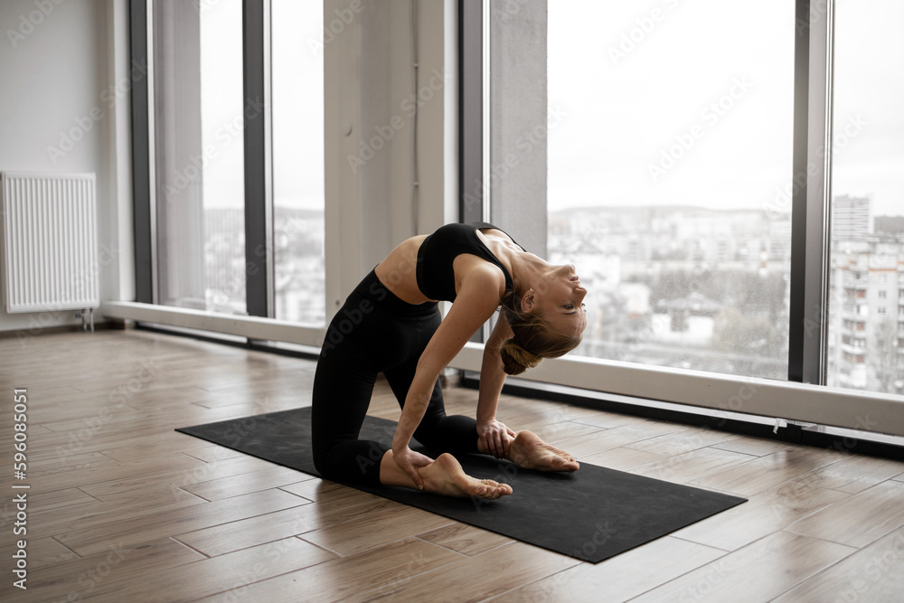 Foto de Athletic caucasian woman with bare feet standing in Camel Pose ...