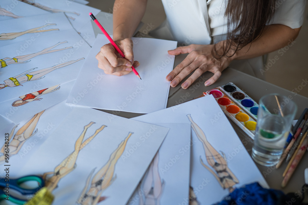 Faceless woman draws sketches of swimwear with a pencil. Close-up of ...