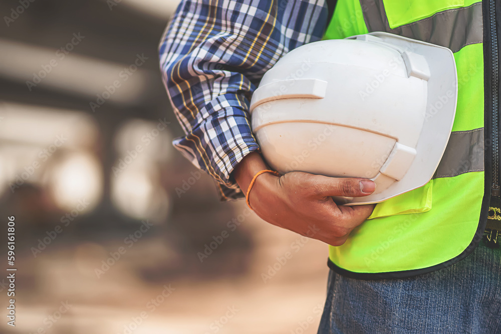 Engineer wearing safety helmet holding plastic helmet standing at ...