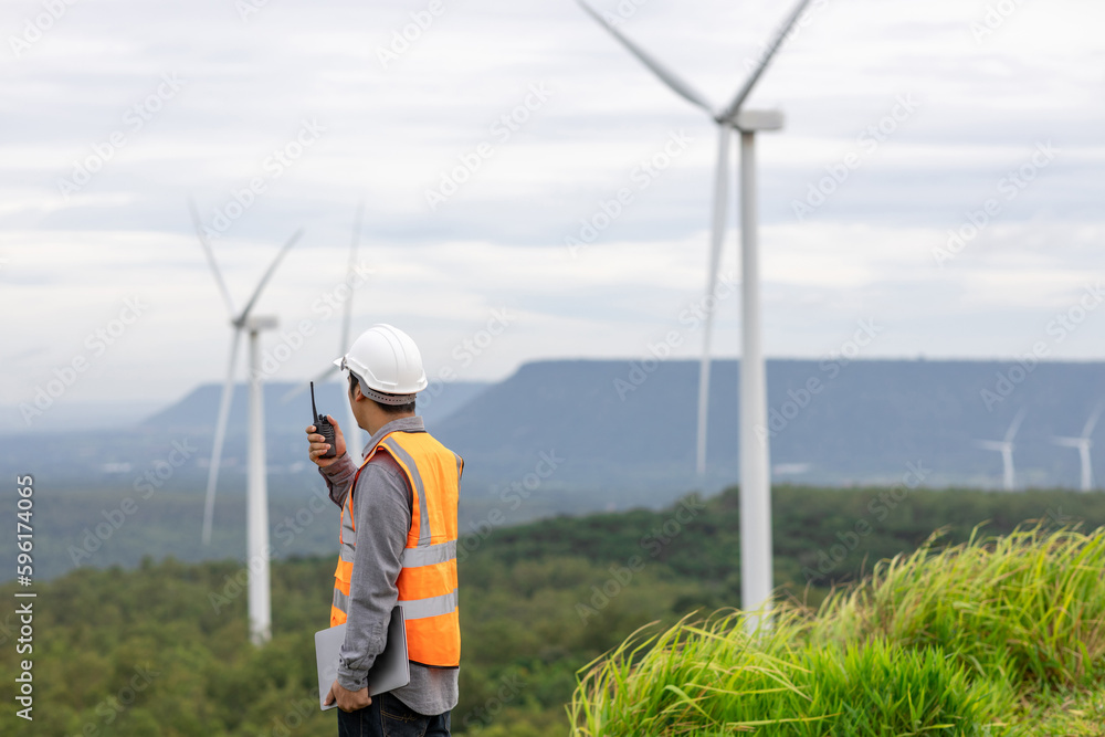 Stockfoto Engineer working on a wind farm atop a hill or mountain in ...