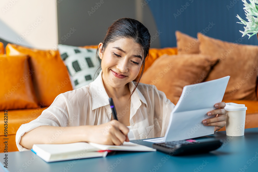 Smiling young asian woman hand press calculator to calculate income ...