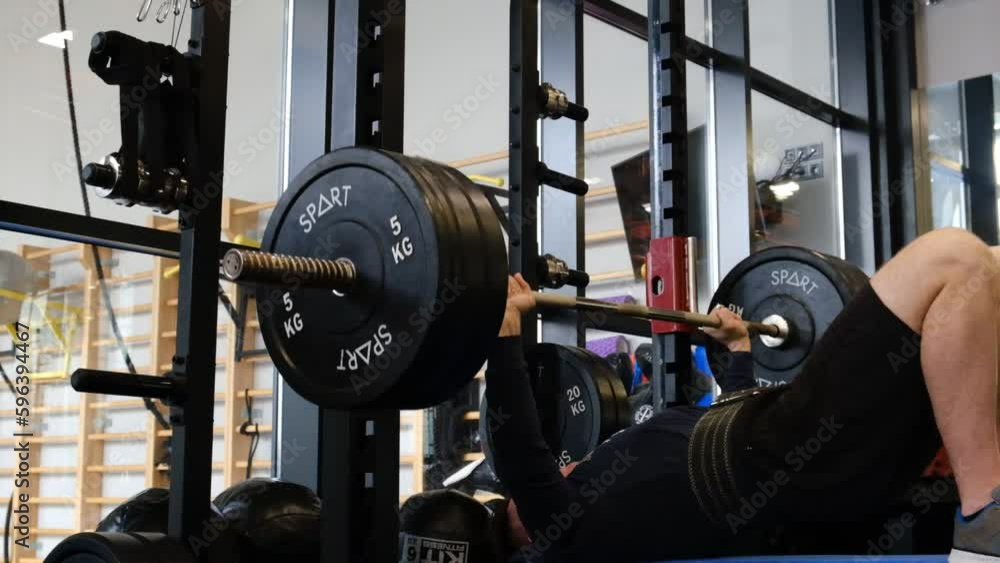 Barbell bench press. A young athlete on a simulator in a supine ...