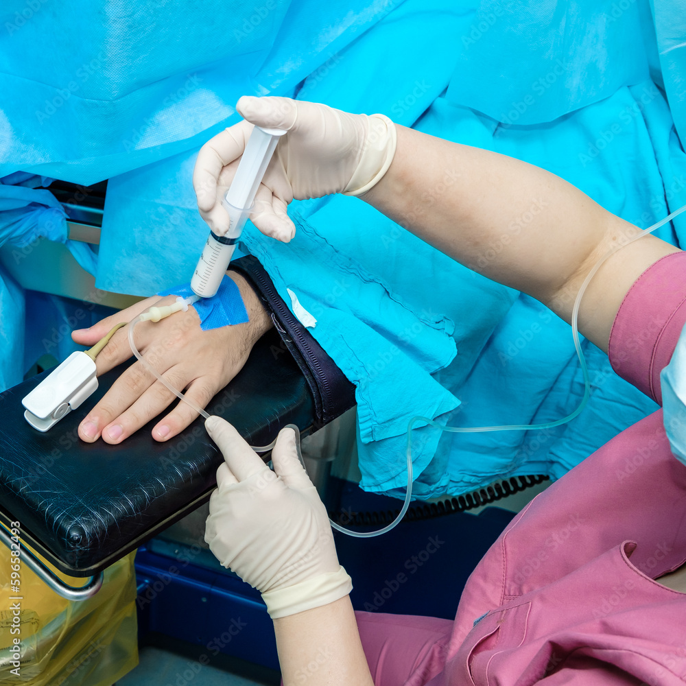 The doctor injects an anesthetic drug with a syringe through a catheter ...