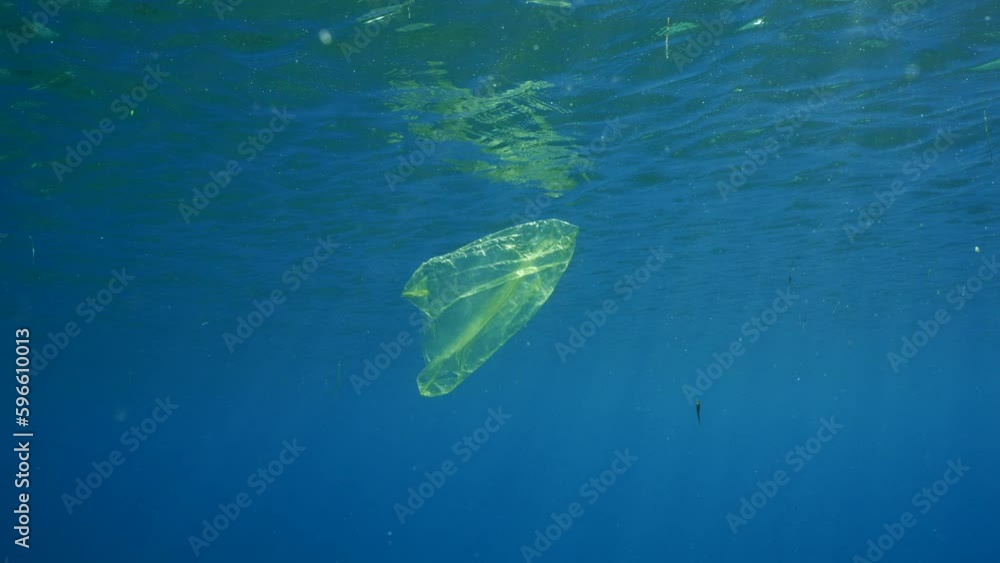Plastic bag floats underwater, slow motion.Yellow plastic bag drifts ...