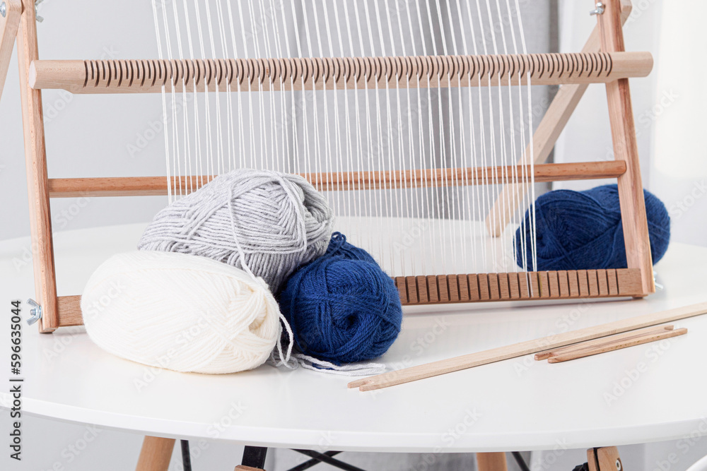Tools for weaving tapestries. Wooden weaving frame and yarn on a table ...