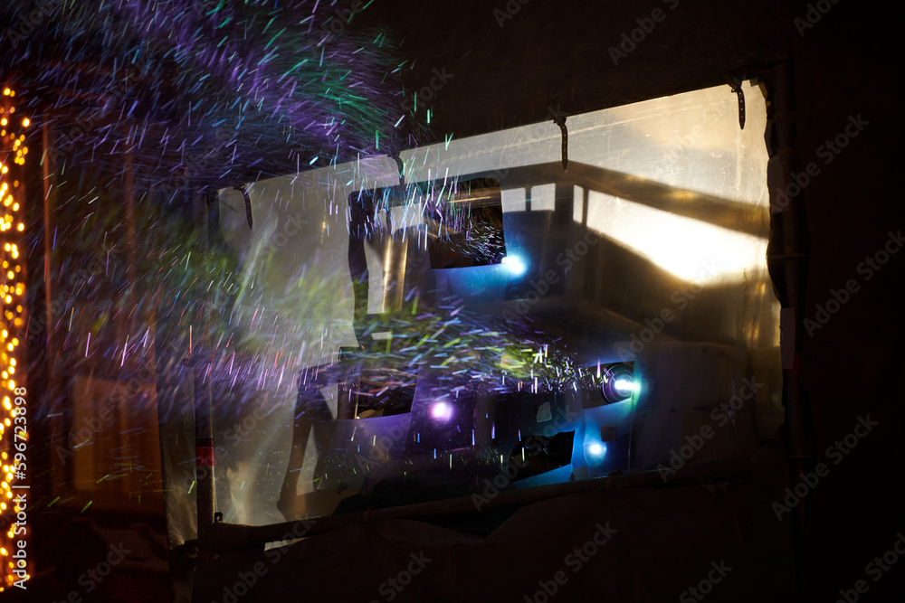 Movie projector lights at outdoor winter film show, blurred snow falls ...