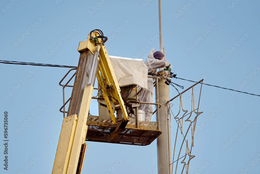 Worker in aerial platform paint street light pole at height. Man in ...