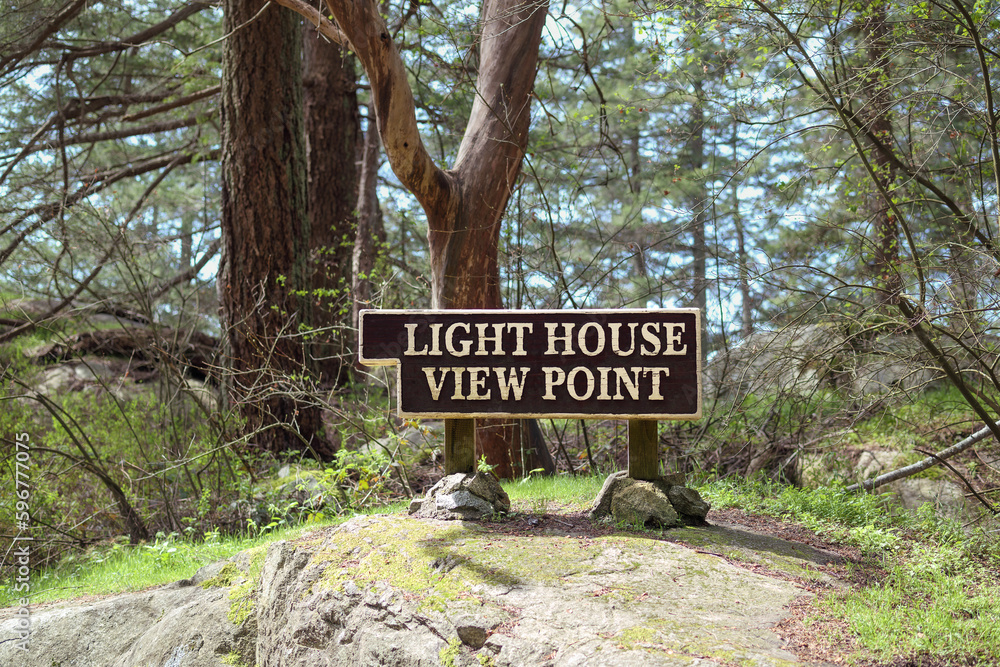 Lighthouse view point signage in park in front of tall tree foliage ...