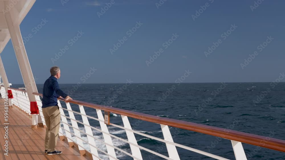 Man on lower deck of cruise ship in heavy seas and swell bracing ...