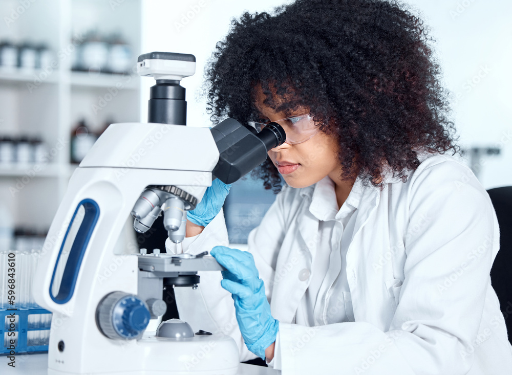 Young african american woman wearing a labcoat and goggles looking at ...