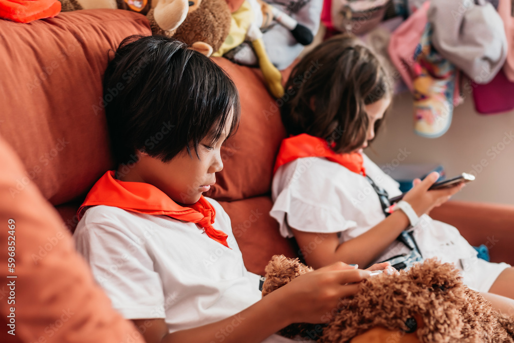 two children play with a cell phone in their room. multiracial. concept ...