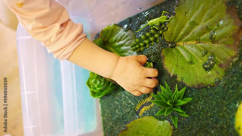 Little girl playing in handmade swamp of green-dyed chia seeds with ...