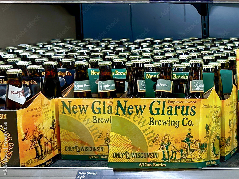 Six packs of New Glarus spotted cow beer sit on a grocery store shelf ...