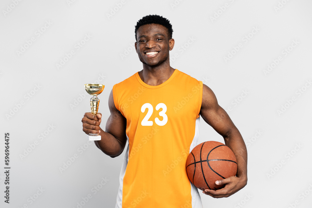Confident smiling African man, basketball player holding trophy cup and ...