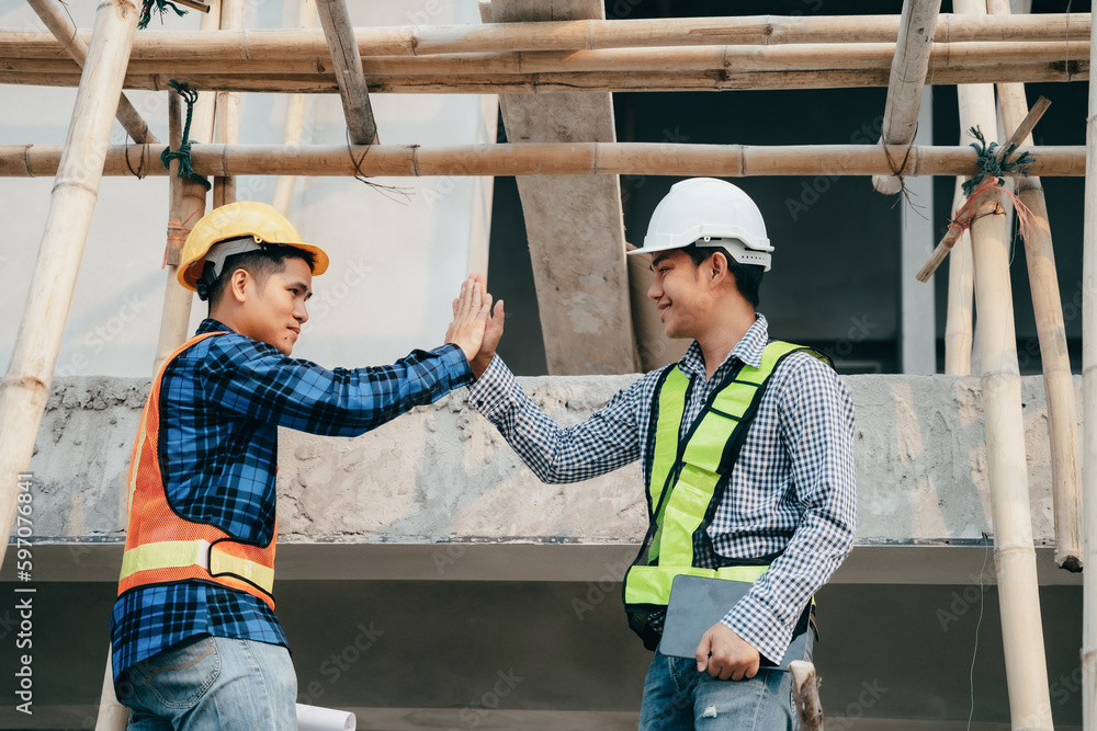 Construction workers, architects and engineers shake hands while ...
