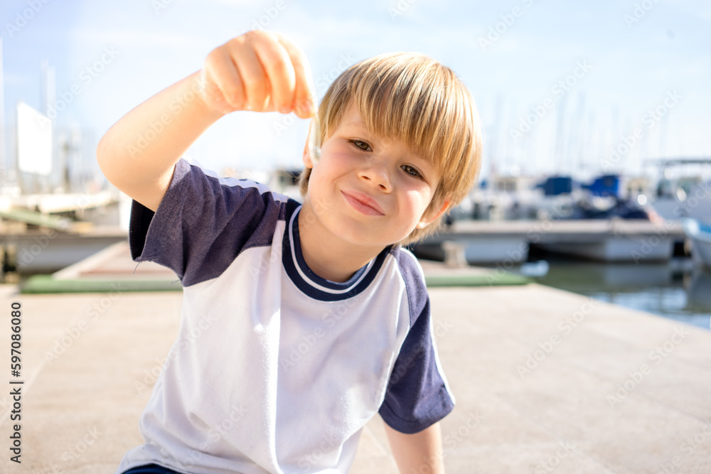 Kid boy showing little fish in yacht club. Sea traveling. Summer ...