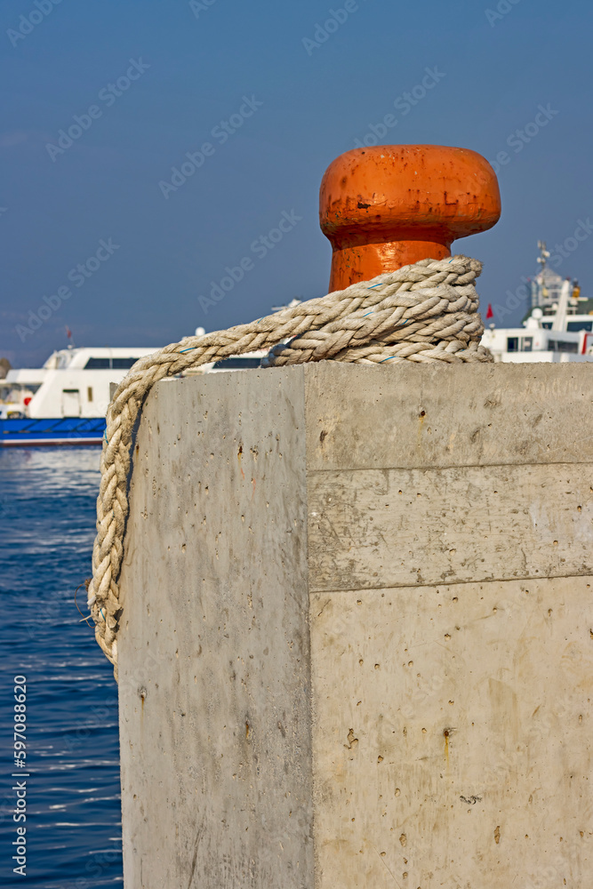 Bright orange mooring pole for mooring ships with a rope wrapped around ...