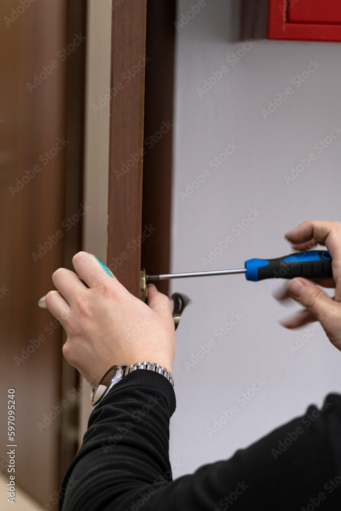 Installation of a door lock on an interior door. The hands of the ...