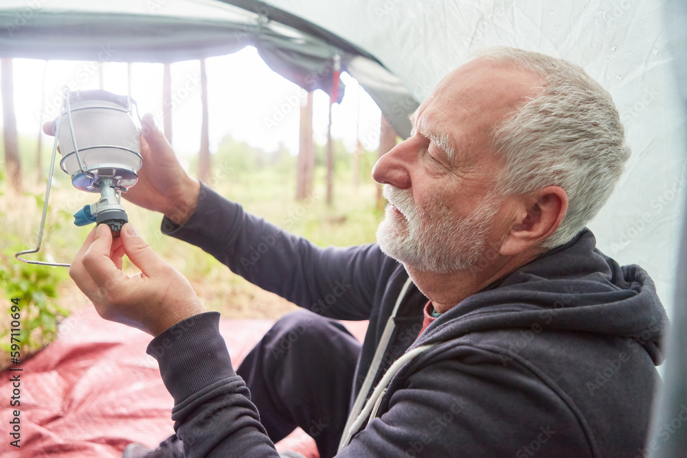 Senior man examining stove burner sitting in tent Stock Photo | Adobe Stock